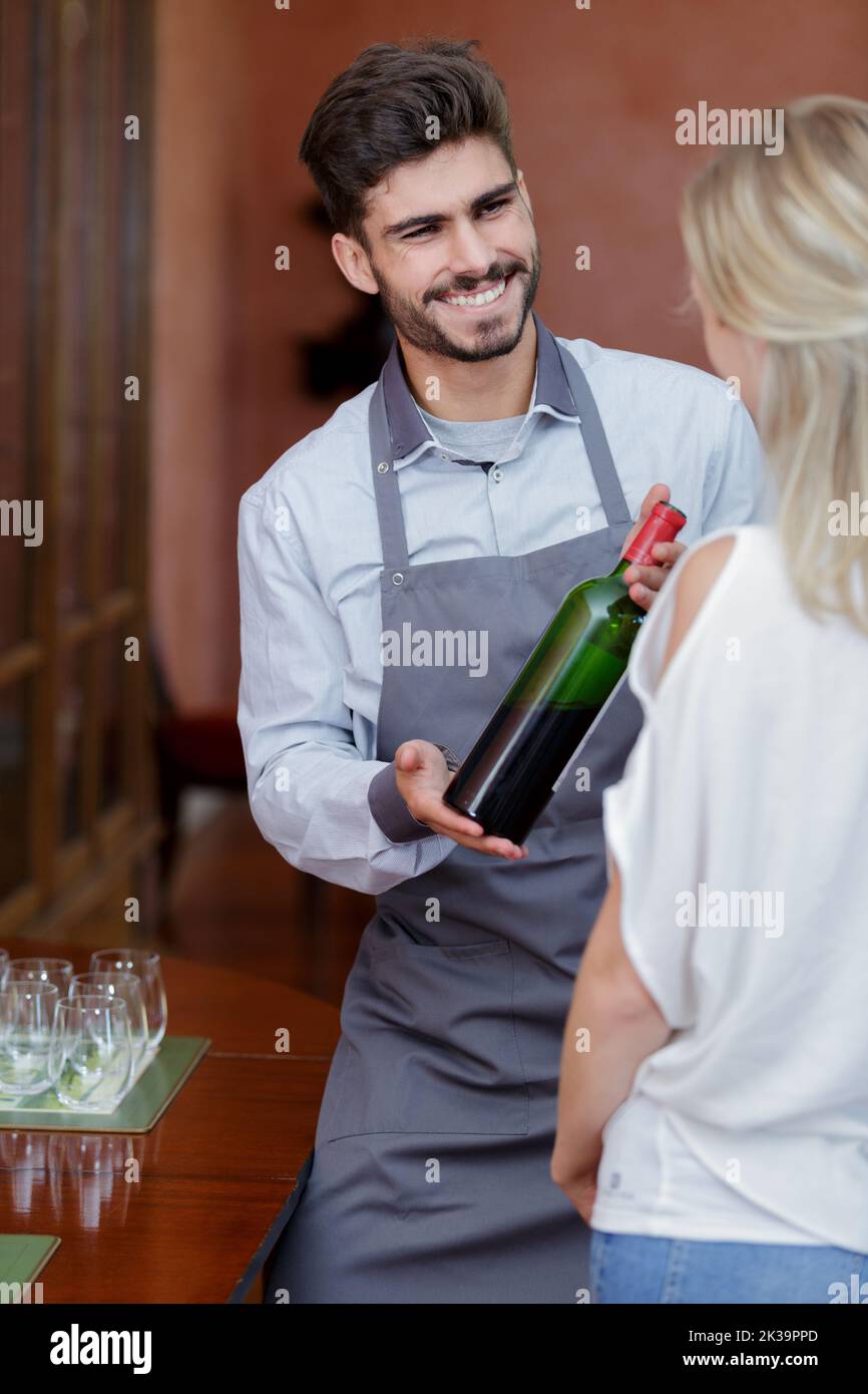 cheerful man wearing apron selling wine in wine house Stock Photo - Alamy