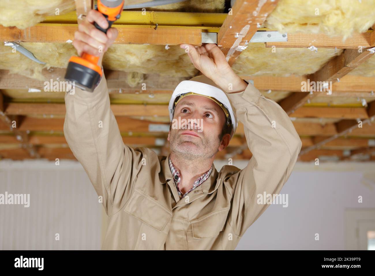 professional builder using drill on ceiling joist Stock Photo - Alamy