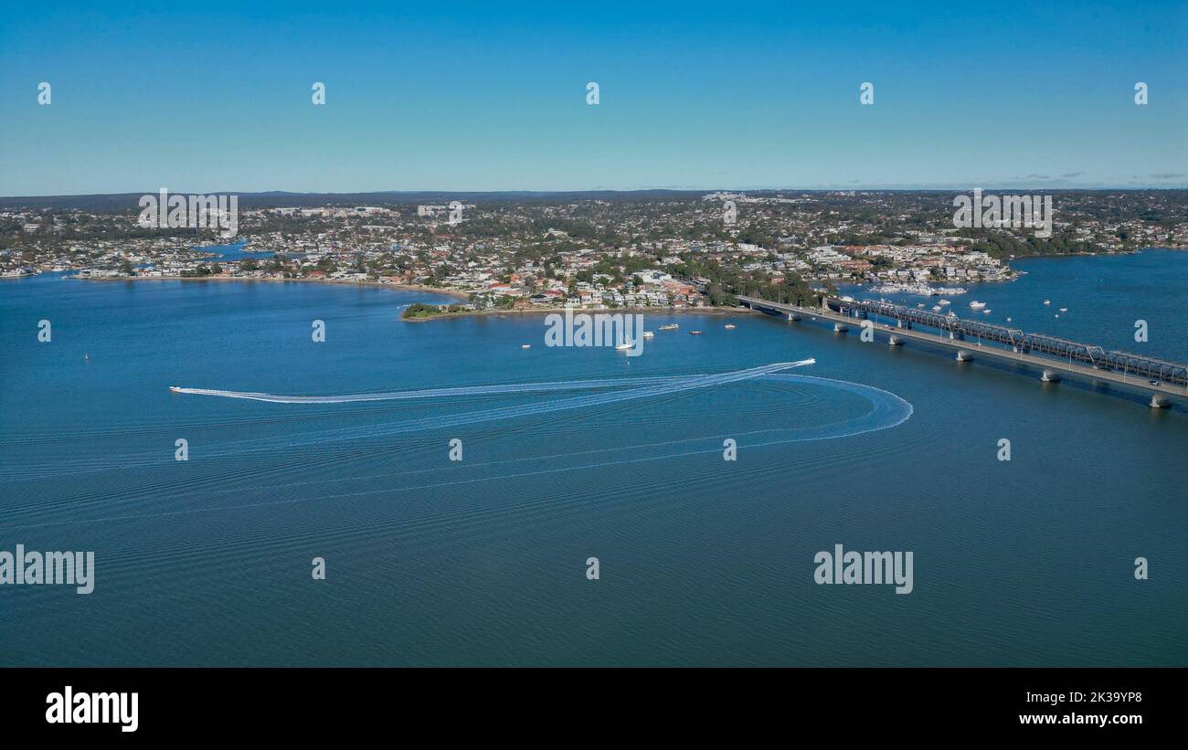 An aerial view of a bridge across the blue ocean with the trails of ...
