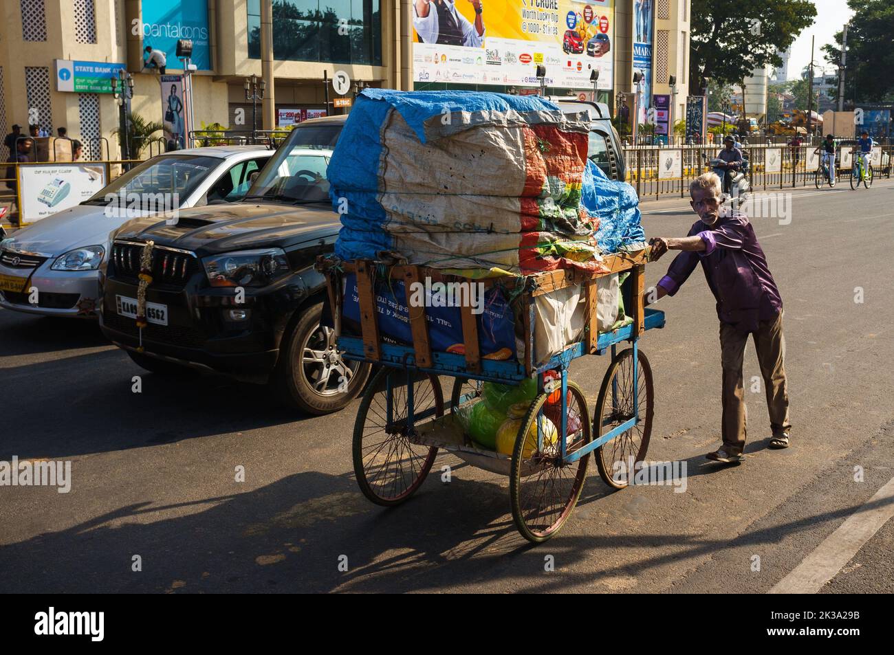 A closeup of an Indian man pushing a loaded cart in the streets of ...
