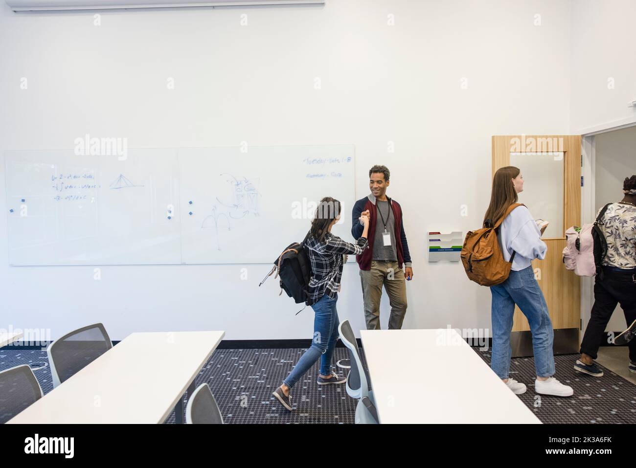 College professor fist bumping student leaving classroom Stock Photo ...