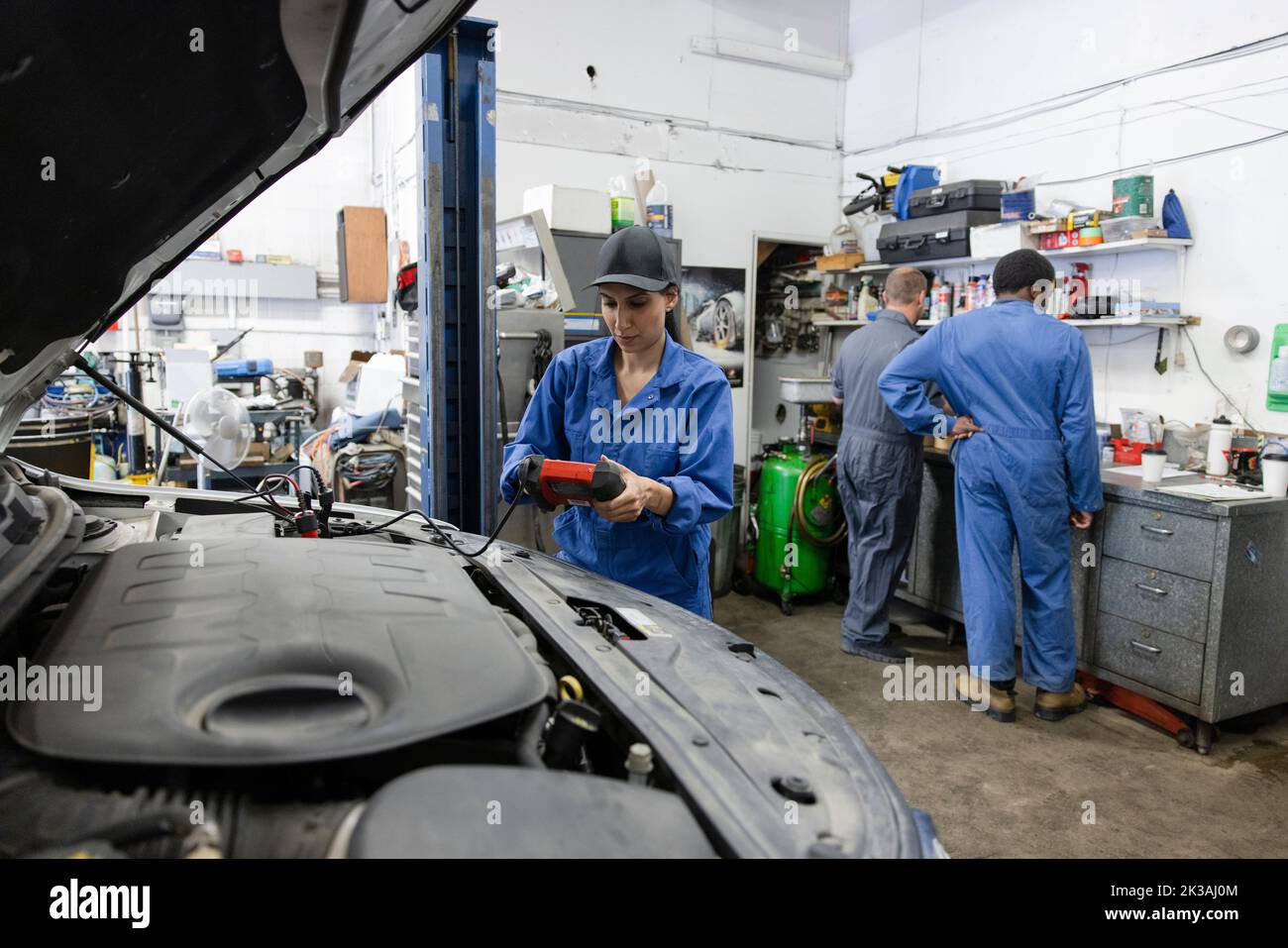 Mechanic looking at scanner plugged into car engine Stock Photo - Alamy