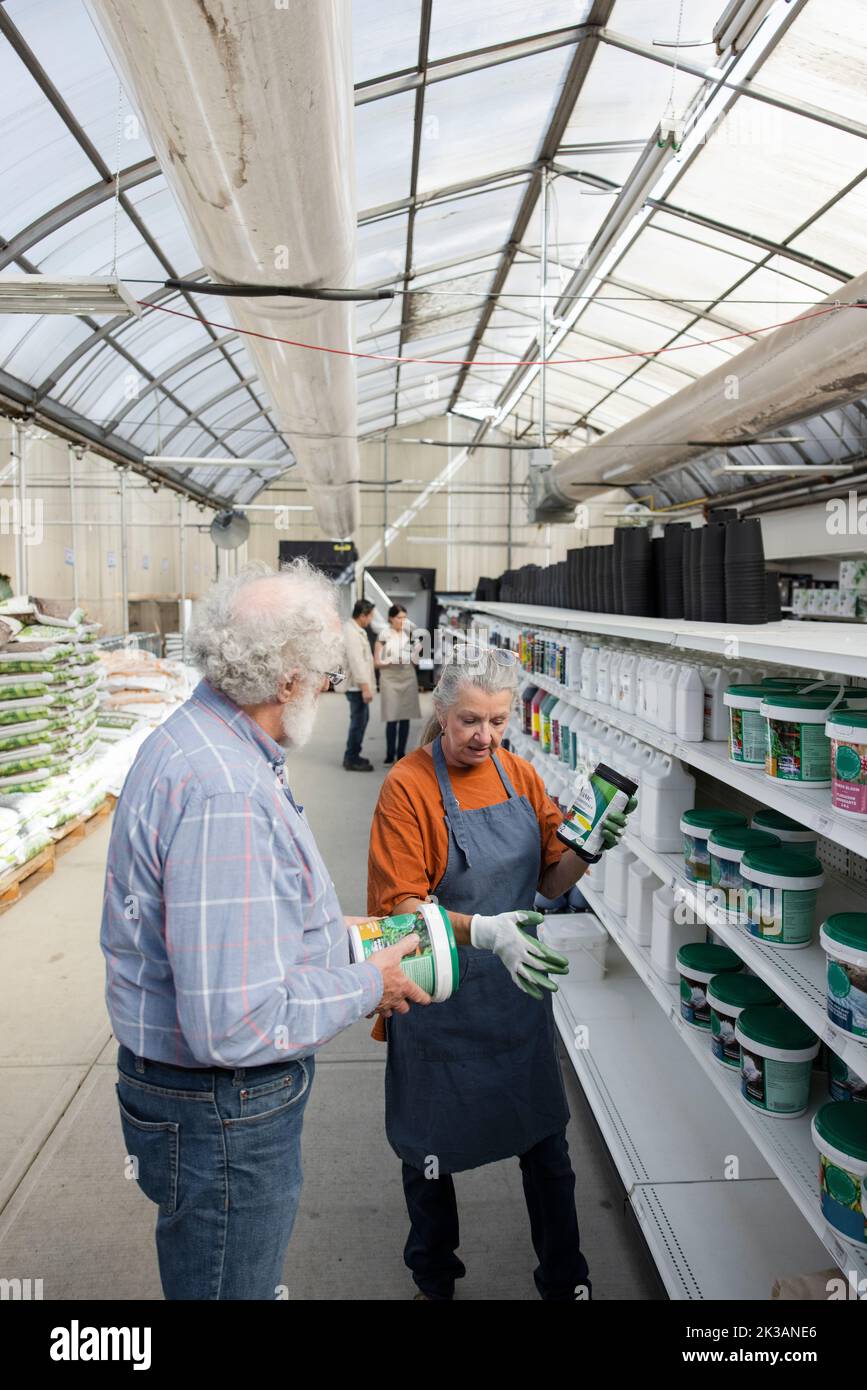 Senior worker assisting customer with products in garden center Stock ...
