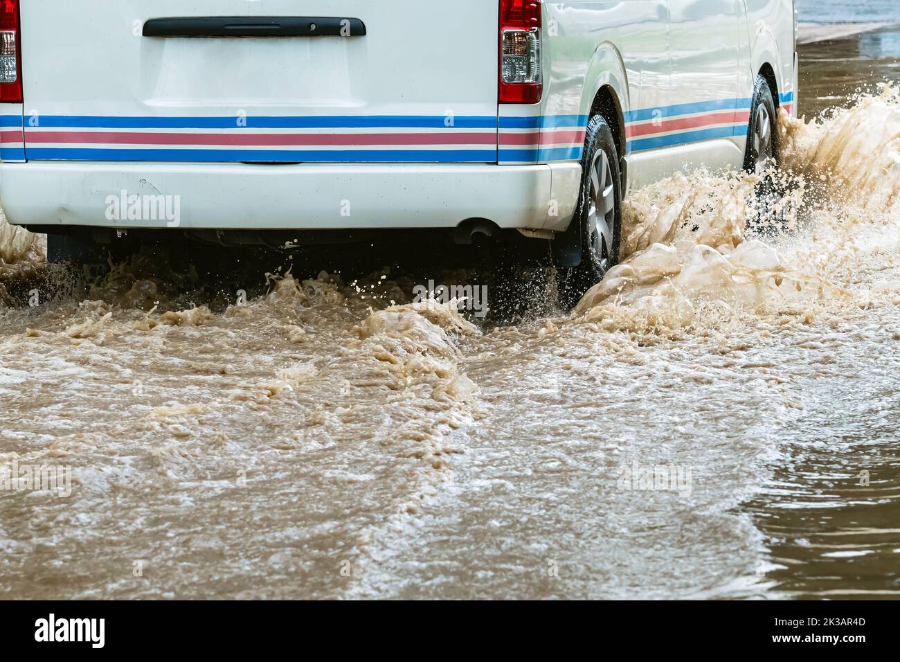White van passing through flooded road. Driving car on flooded road ...