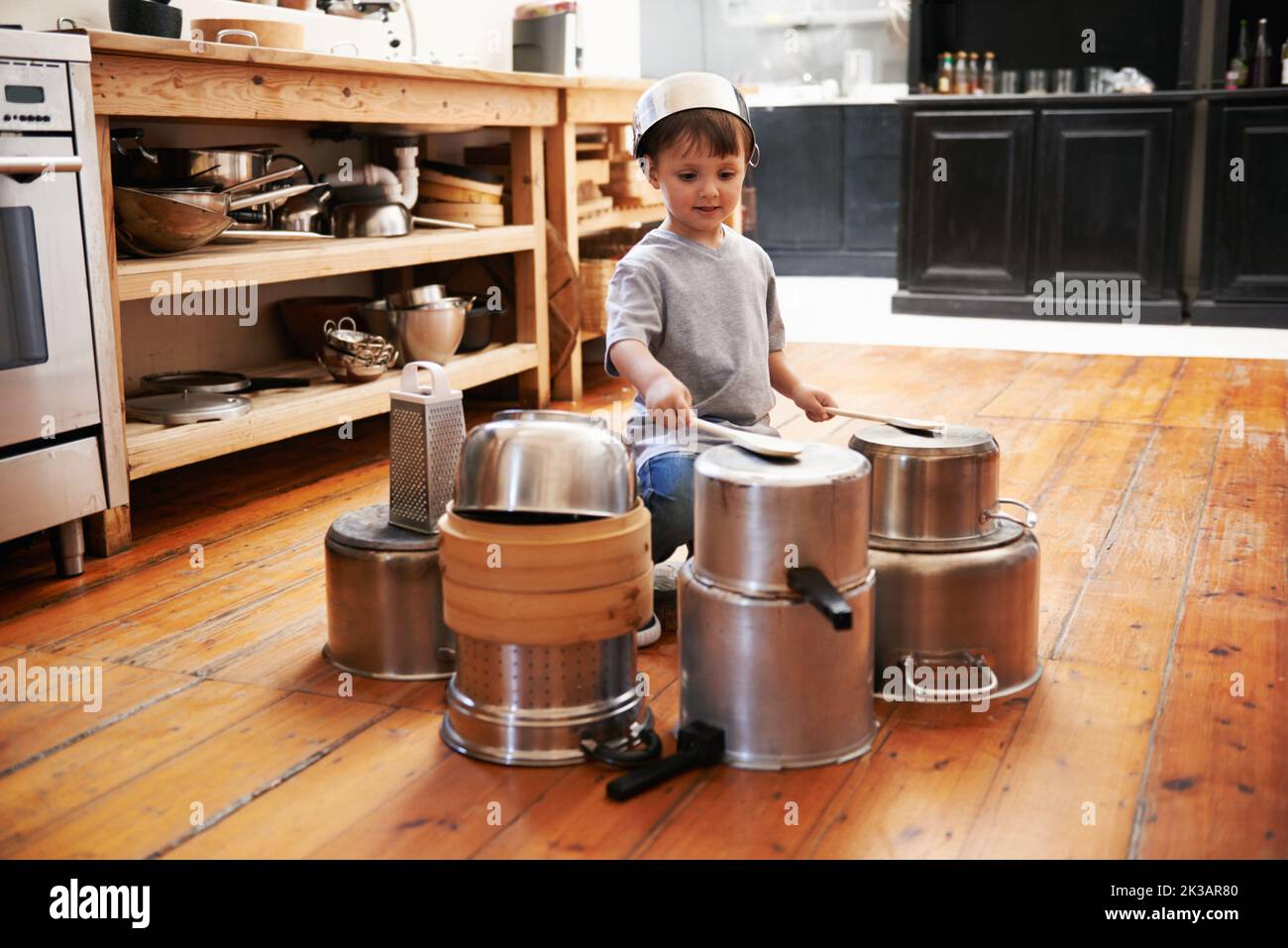 Rock star in the making. A young boy playing drums on pots and pans ...