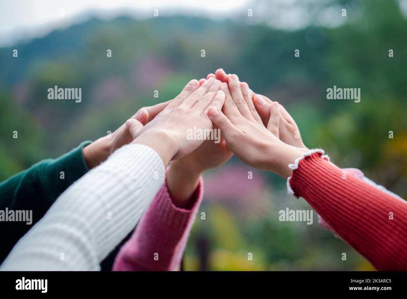 A diverse group of people connects their hands as a supportive sign ...