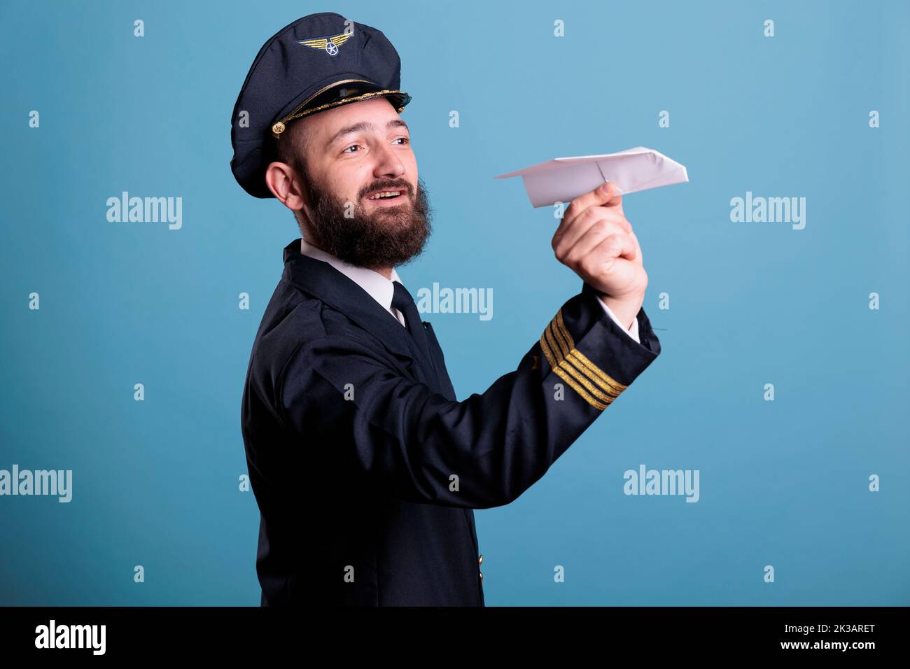 Pilot in professional uniform launching paper plane, holding jet model ...
