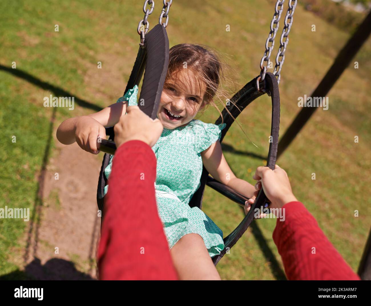 Lets make me go high. a little girl being pushed on a swing outside ...