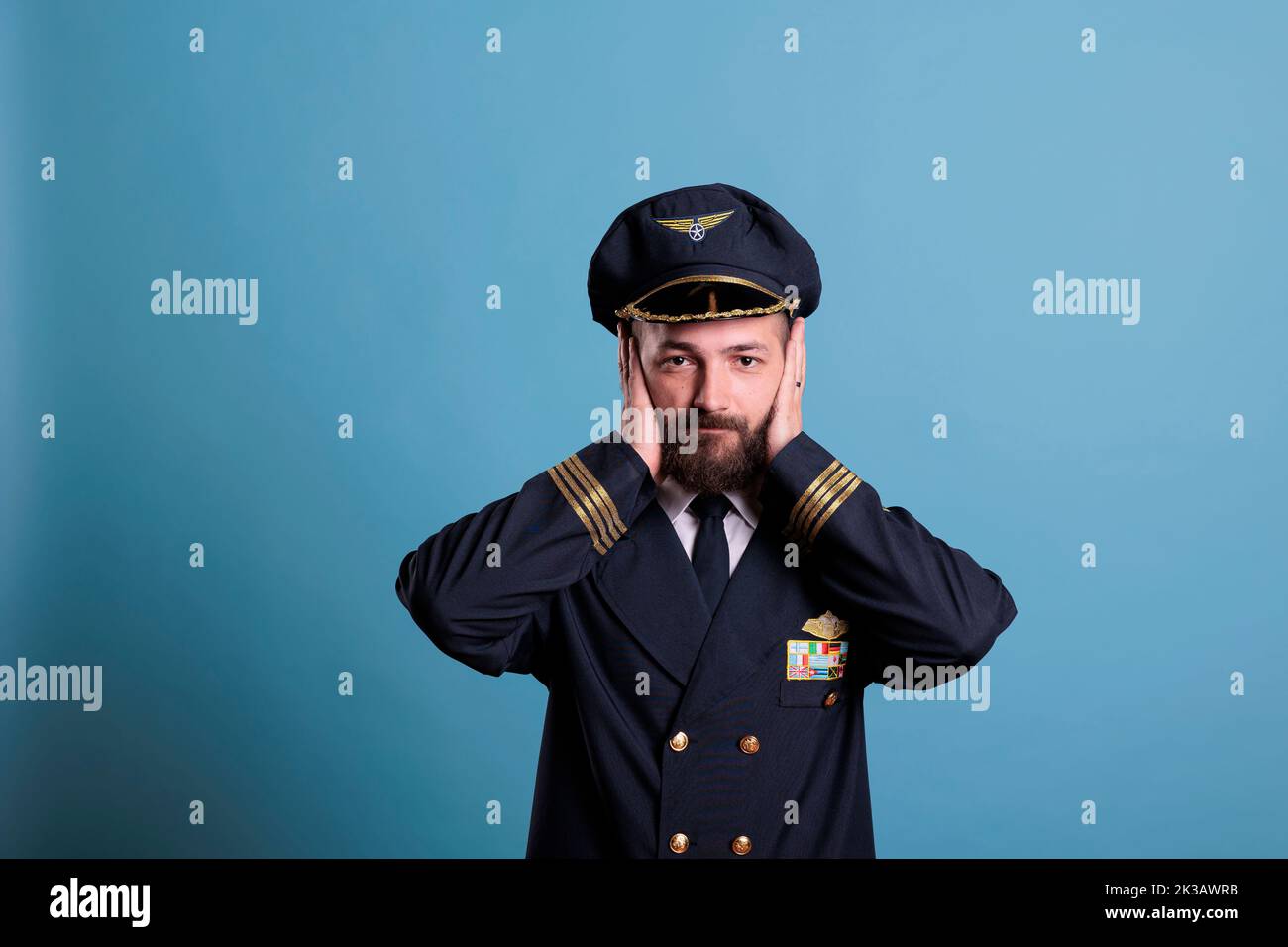 Airliner pilot covering ears with hands, showing see no evil, hear no ...