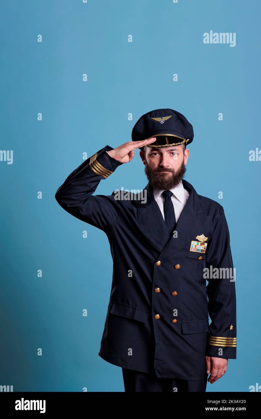 Confident airplane aviator saluting, wearing uniform and hat front view ...