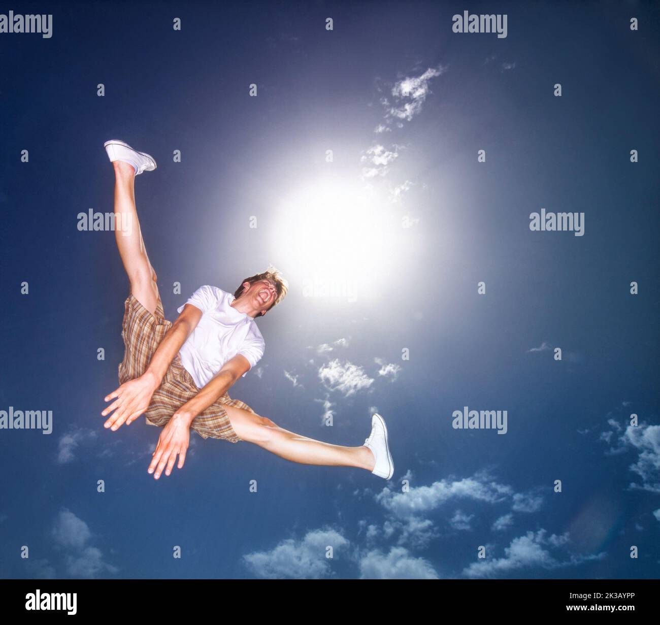Jump to the sun. Jumping acrobat boy high up in the sky with the sun at ...