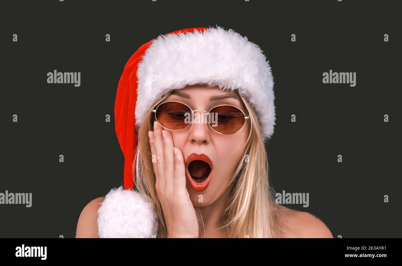 Portrait of surprised woman with her mouth open in a santa hat and ...