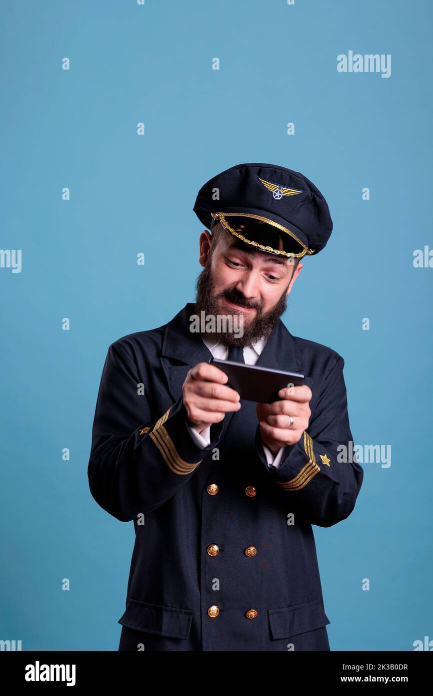 Airplane captain in professional uniform playing mobile games on ...