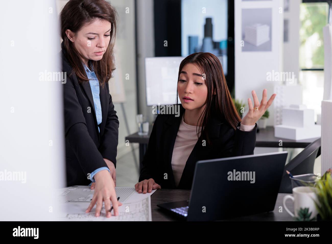 Architects working with blueprints, discussing drafts in coworking ...