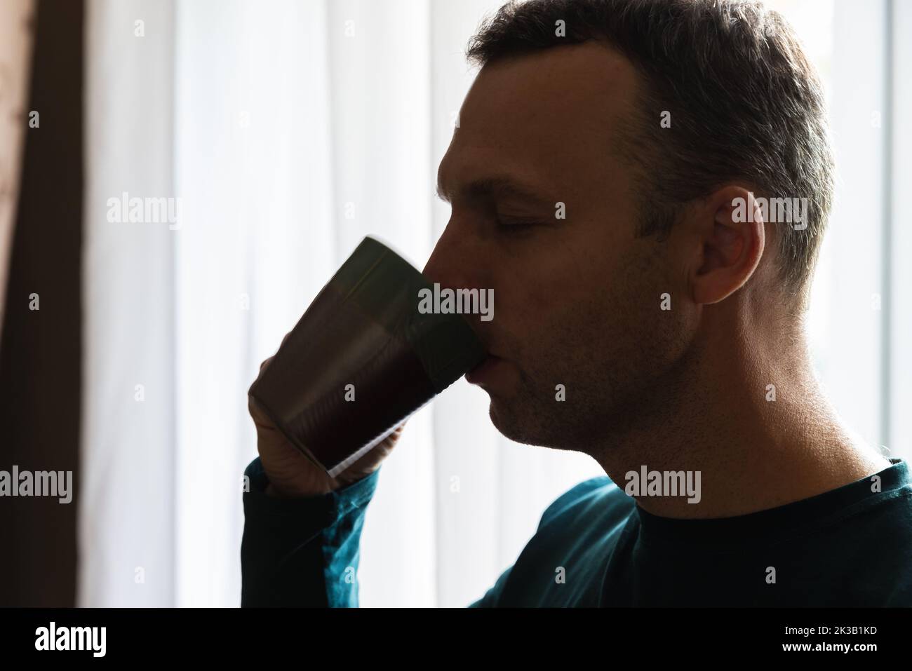 Artistic low key portrait of young adult Caucasian man drinking coffee ...