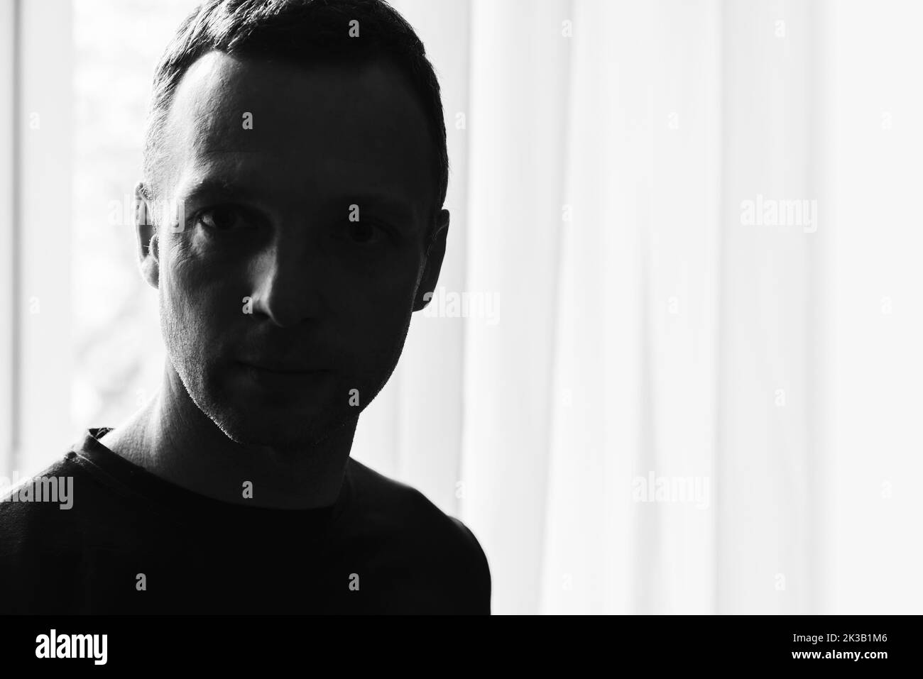 Dark studio face portrait of young adult Caucasian man standing in ...