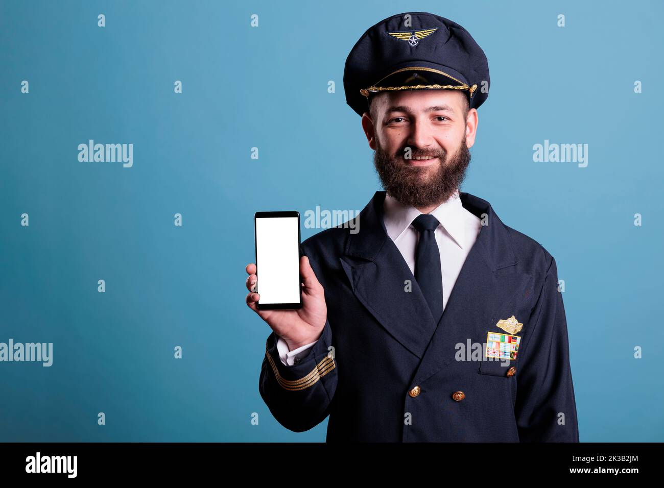 Smiling airplane captain showing modern phone with blank white screen ...