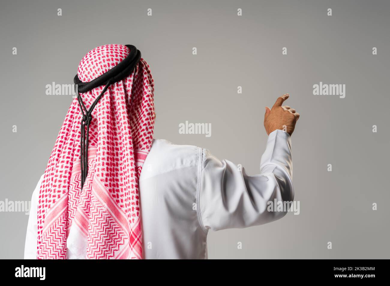 Back view of young Arab man standing on gray background Stock Photo - Alamy