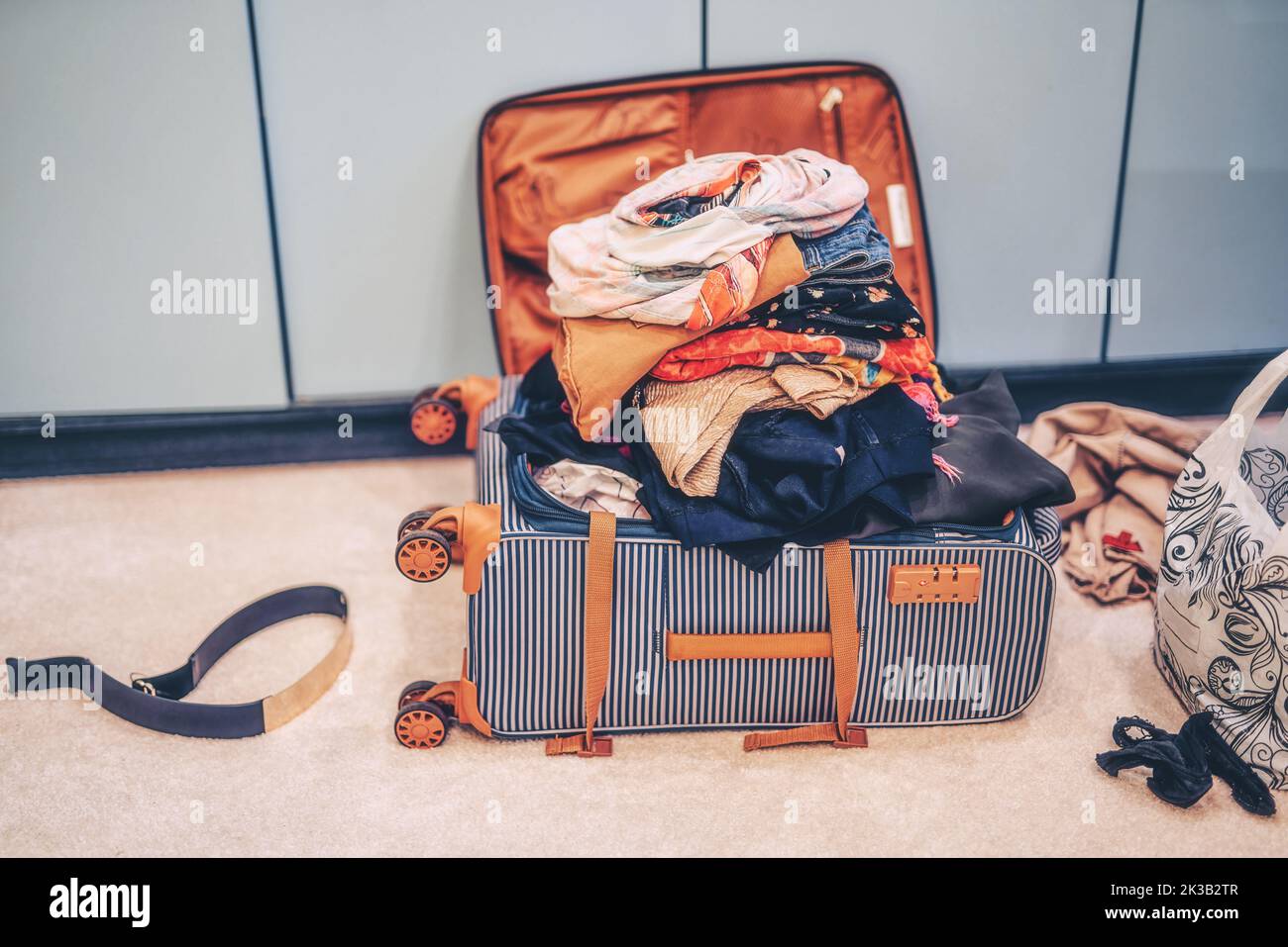 Open suitcase full of clothes in room Stock Photo - Alamy