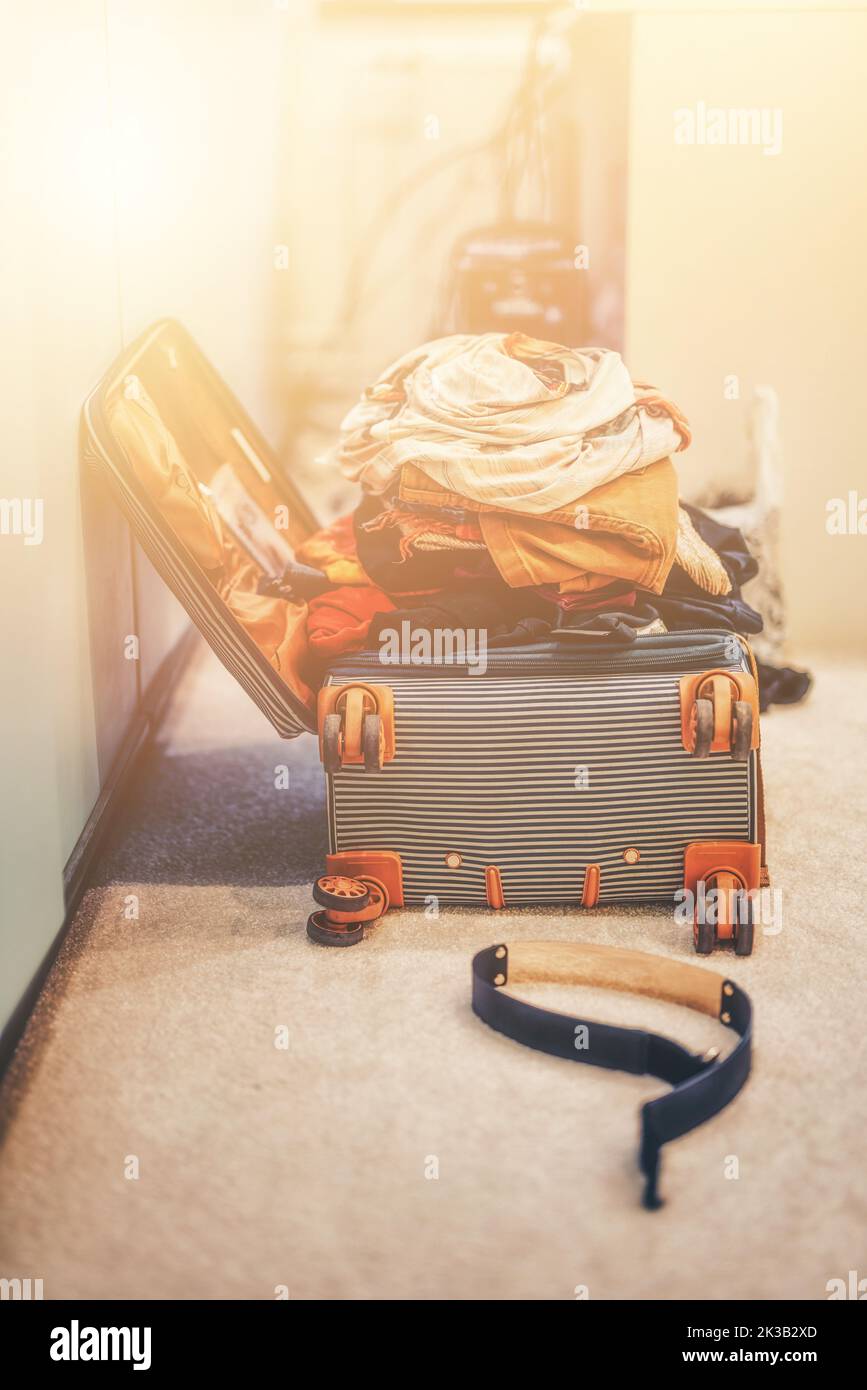 Open suitcase full of clothes in room Stock Photo - Alamy