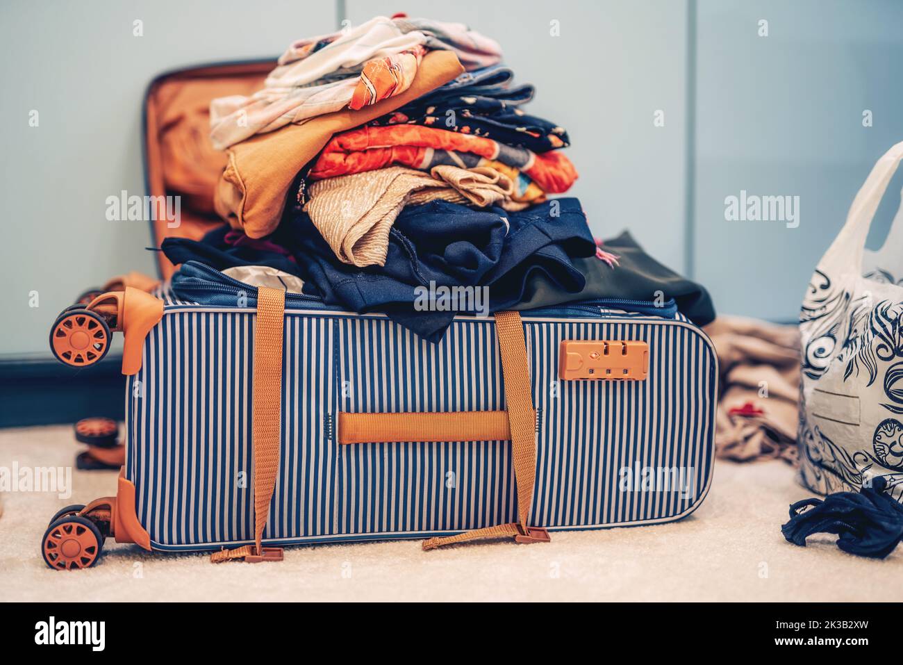 Open suitcase full of clothes in room Stock Photo - Alamy