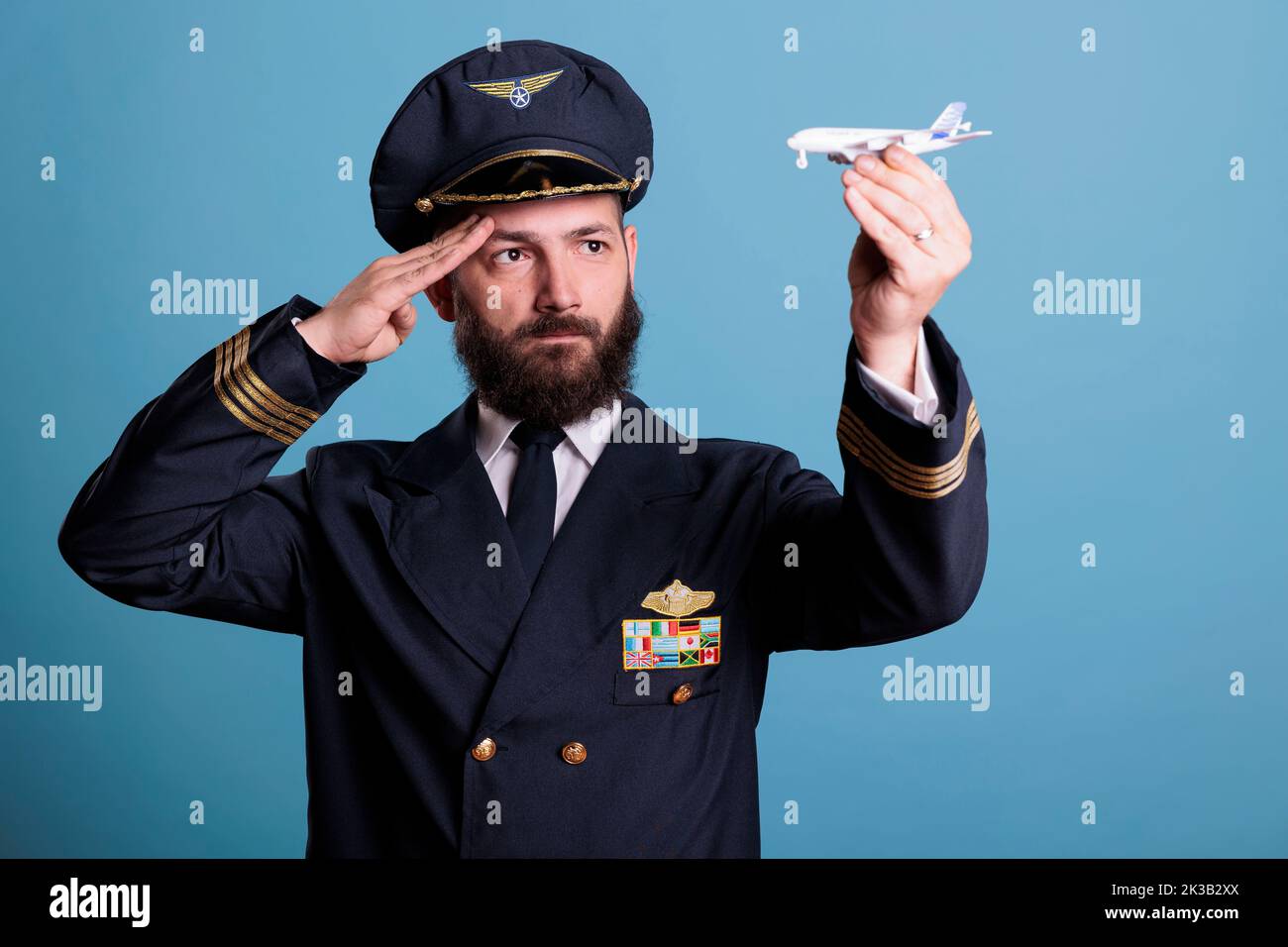 Serious aviator in uniform saluting to small airplane model, Plane ...
