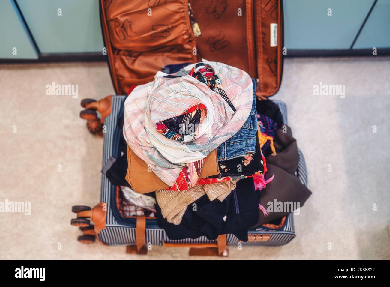 Open suitcase full of clothes in room Stock Photo - Alamy