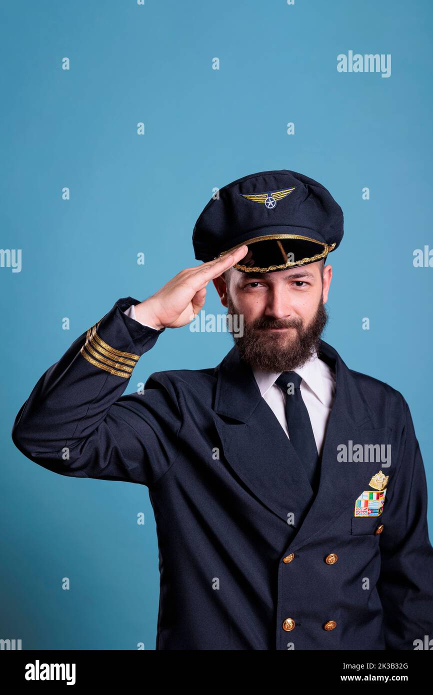 Smiling plane pilot saluting, wearing uniform and hat front view ...