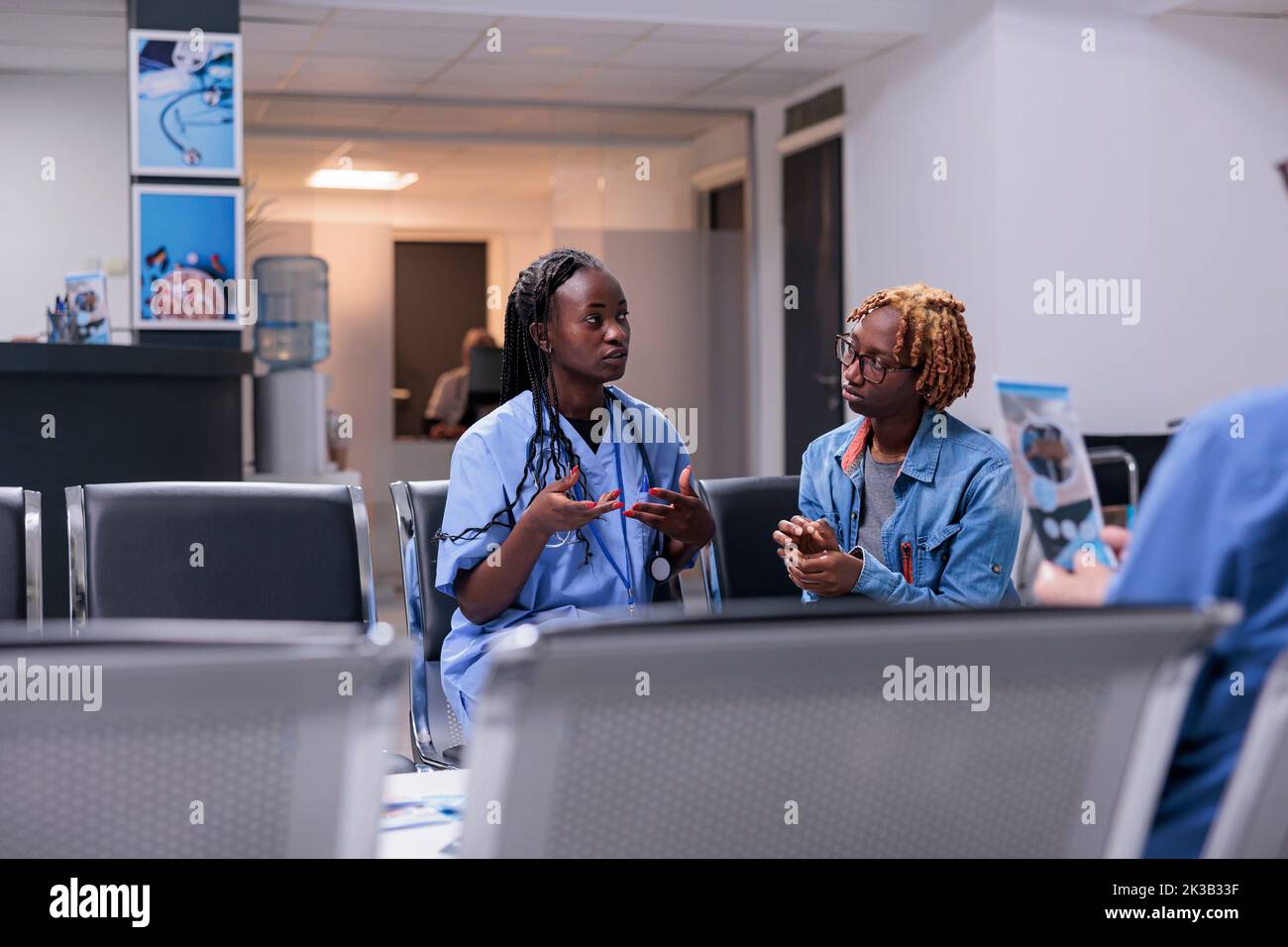 Medical assistant consulting woman at clinic, talking about disease and ...