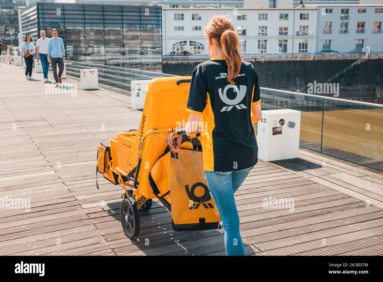 23 July 2022, Dusseldorf, Germany: Postman with Deutsche Post mail ...