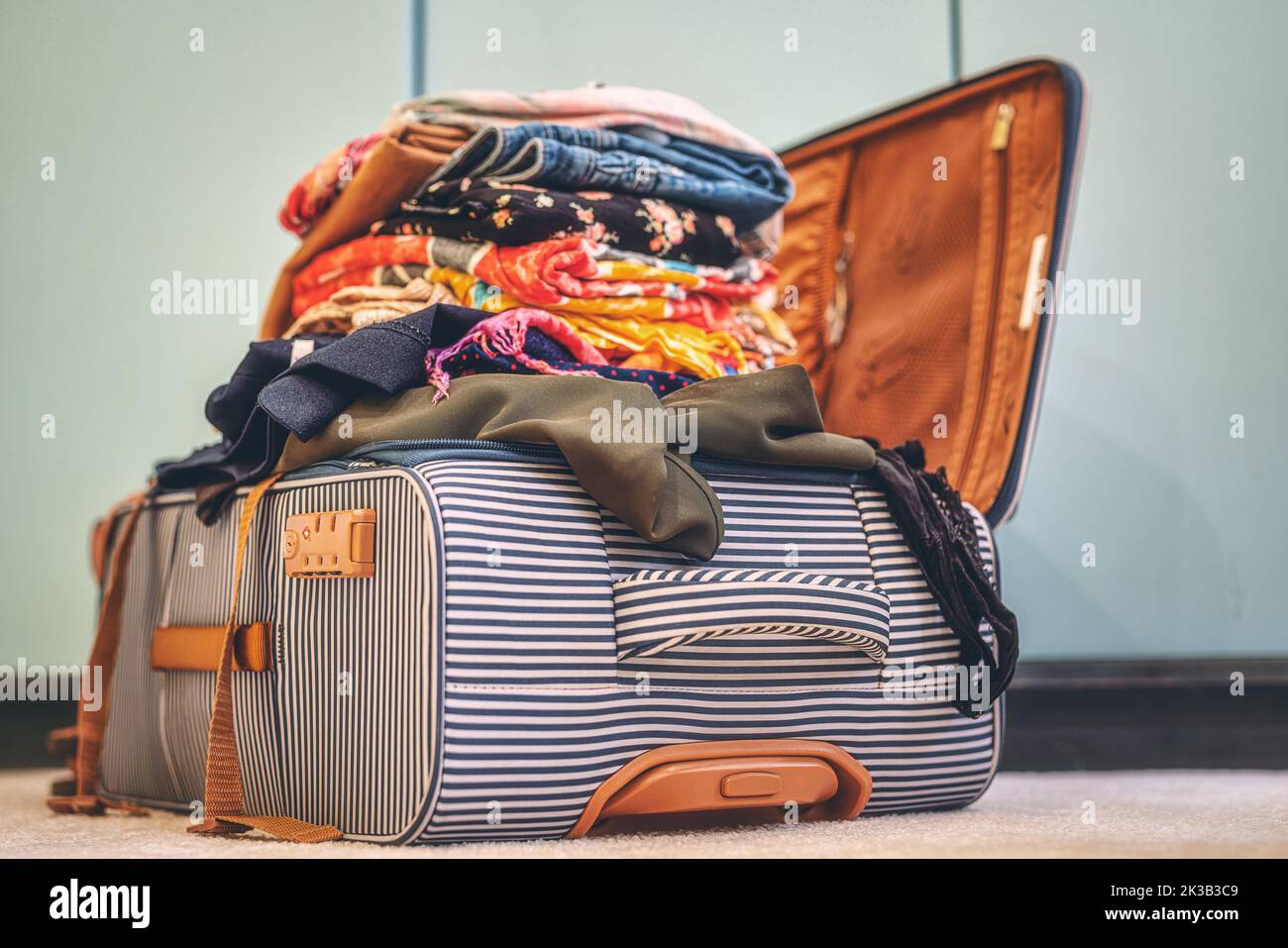 Open suitcase full of clothes in room Stock Photo - Alamy