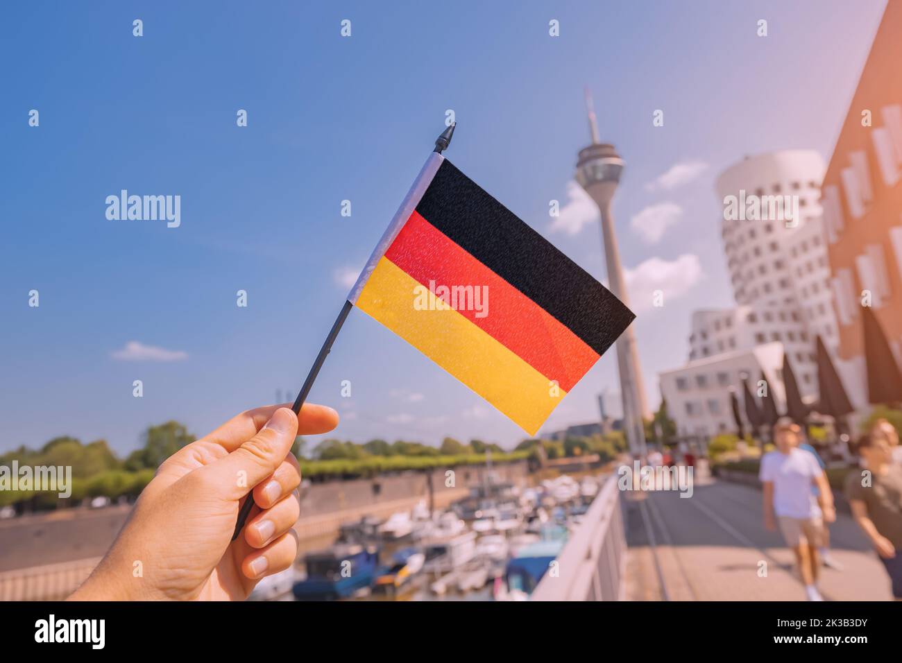 German national flag in hand at the Media Harbor and TV-tower in ...