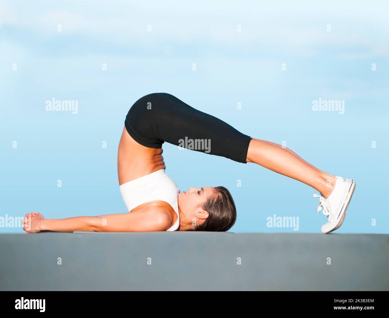 Shes super flexible. A young woman doing yoga stretches outdoors Stock ...