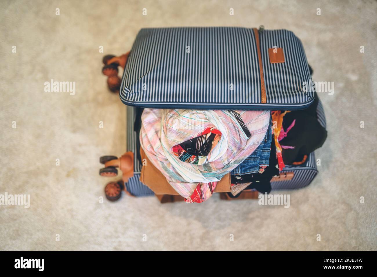 Open suitcase full of clothes in room Stock Photo - Alamy