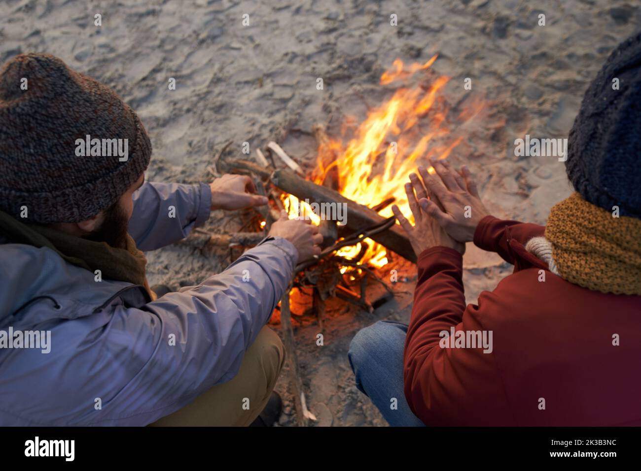 Its cold this morning. Two young men sitting around a fire on the beach ...