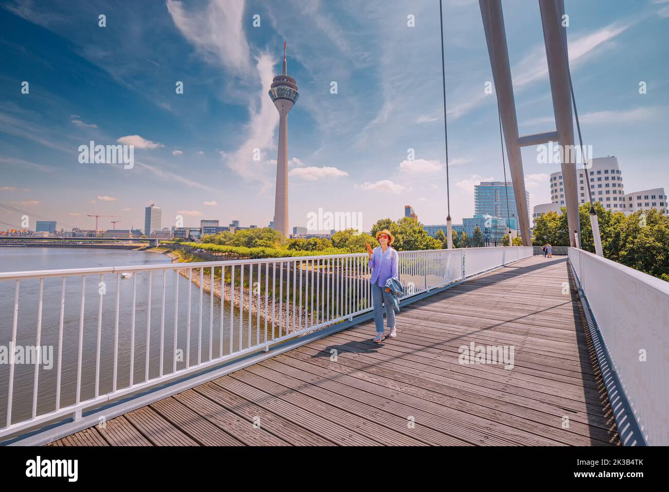 Girl traveler walking by pedestrian footpath bridge over Rhine river ...