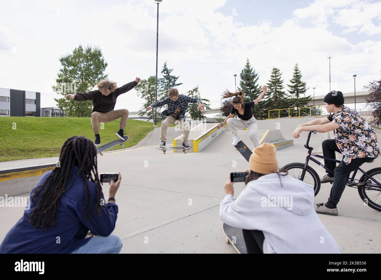 Teen girls filming friends doing skateboard tricks in skatepark Stock ...