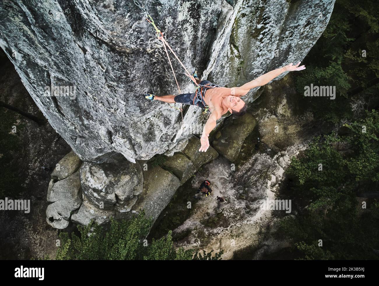 Young man climber climbing on high boulder with rope. Fearless rock ...