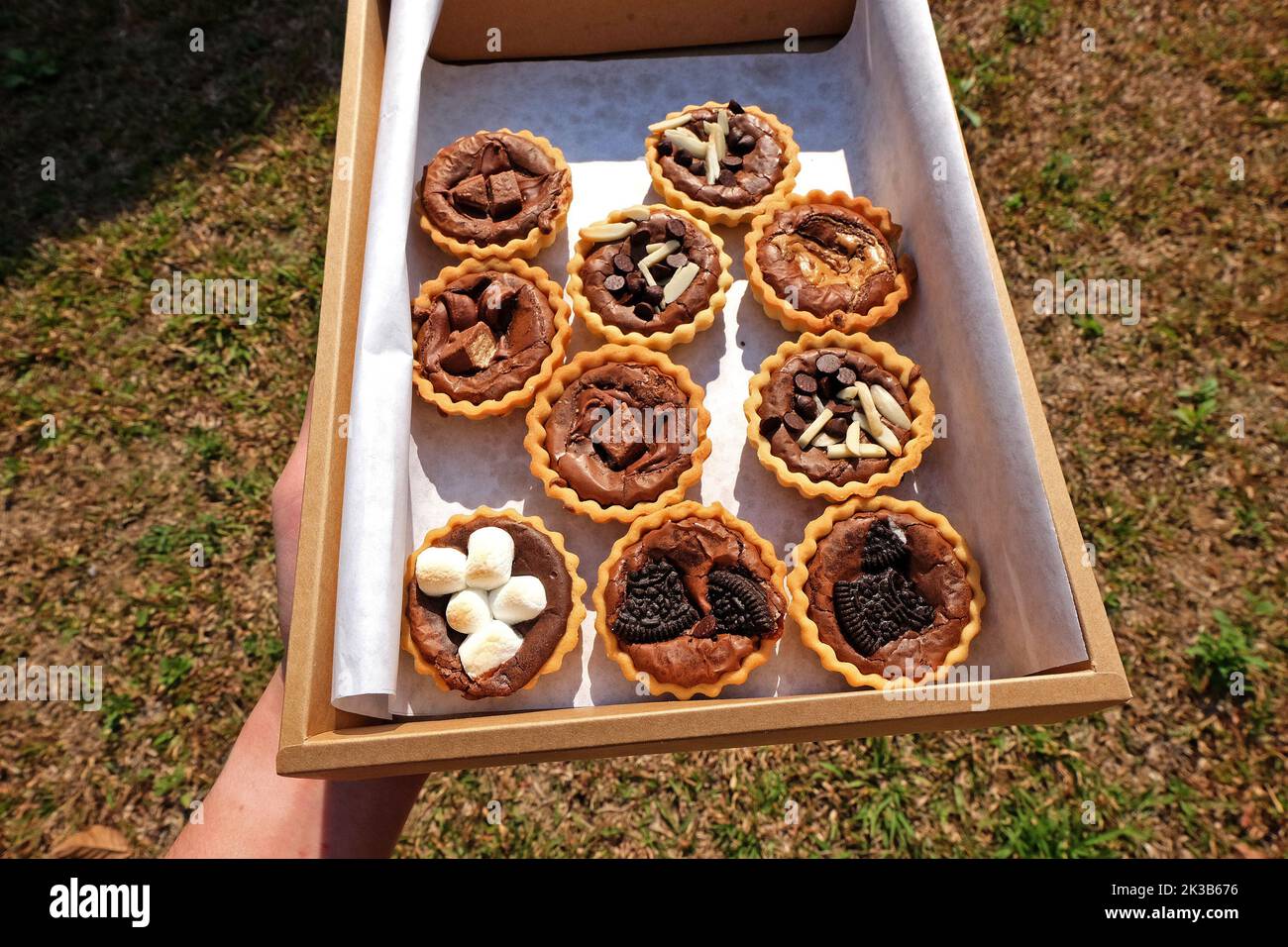 Close up paper box of Chocolate fudge brownie tarts topped with Sliced ...