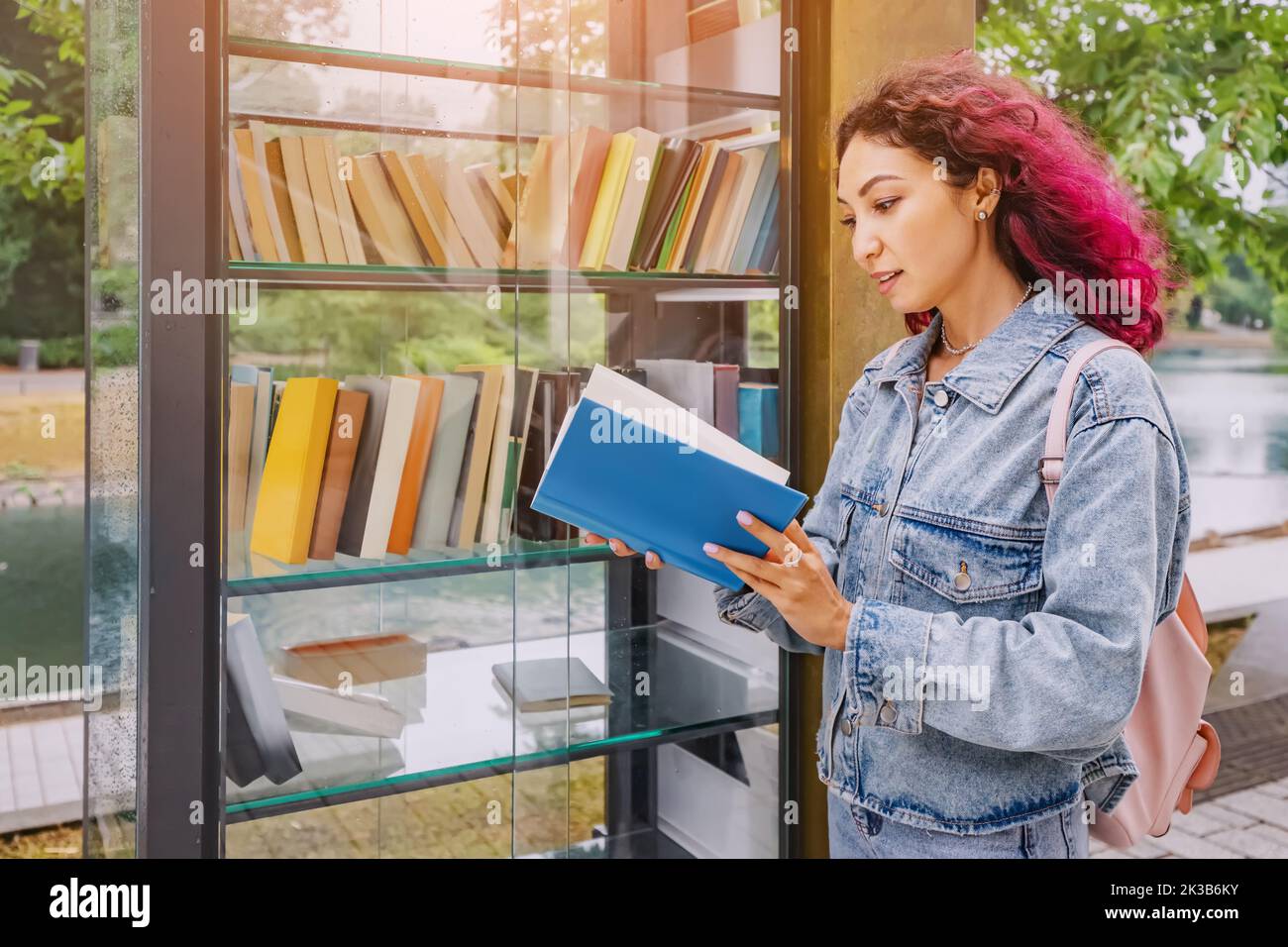 Girl choosing books at free open public library at city park for book ...