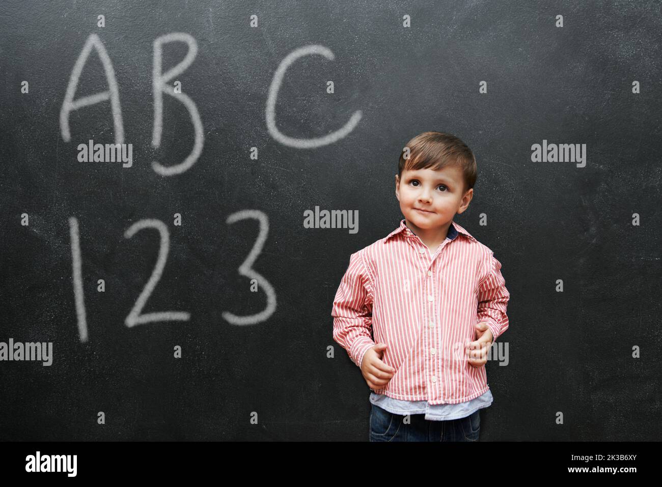Hes a star pupil. A young biy standing in front of a blackboard with ...