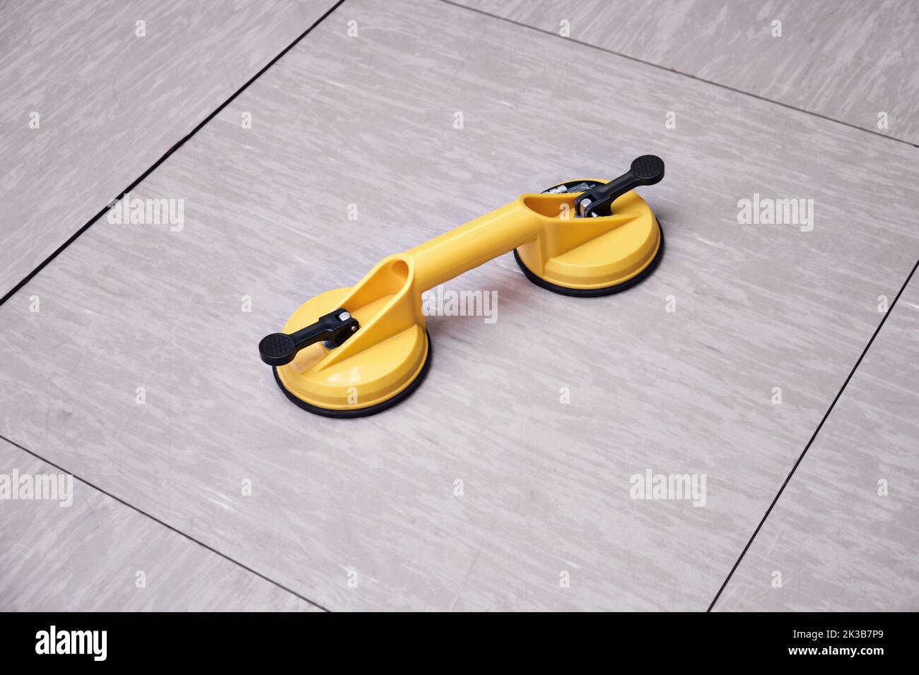 Yellow handheld device with vacuum suction cups for lifting floor ...