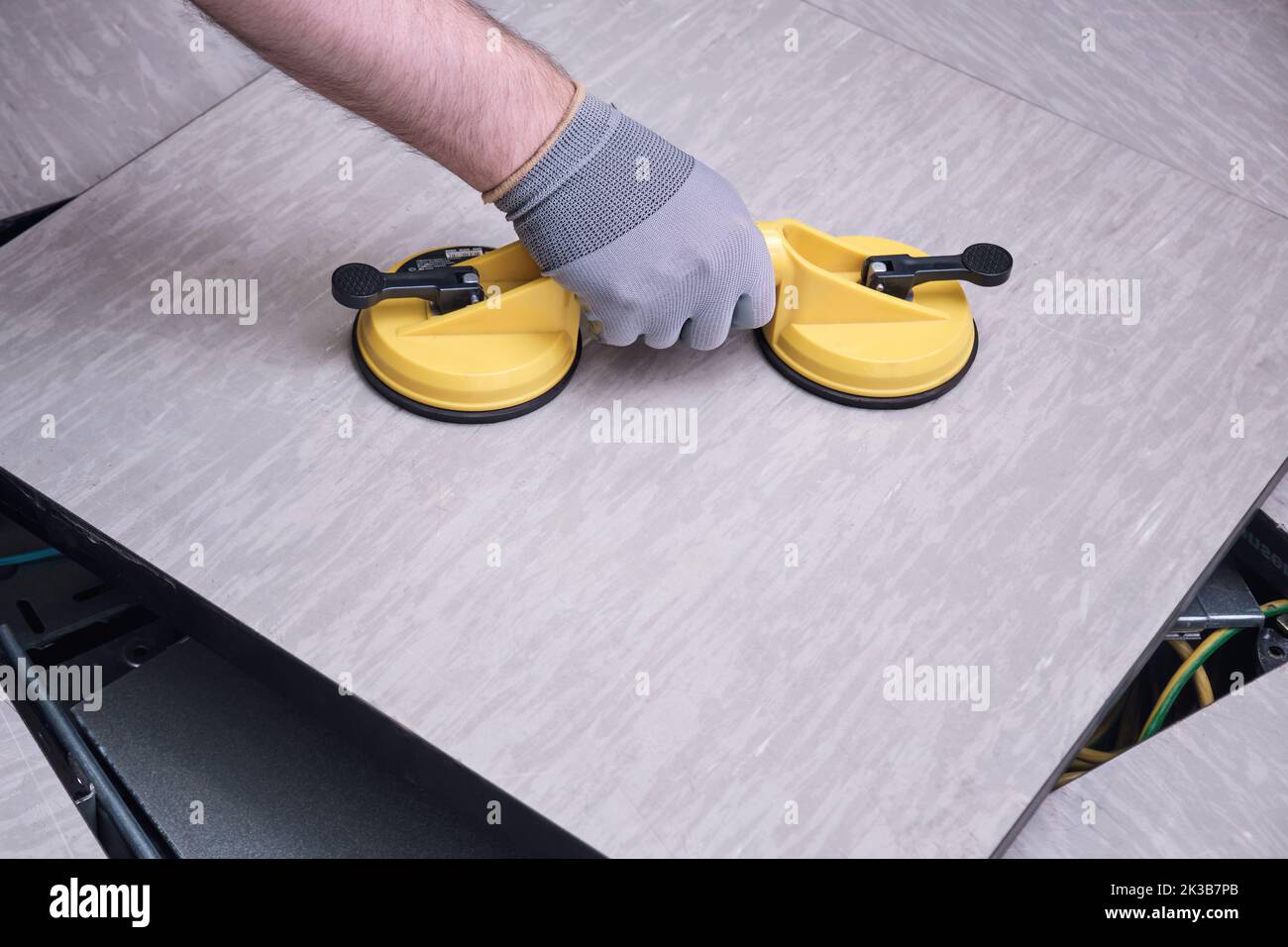 Worker hands with vacuum suction cups for lifting floor panels. A man ...