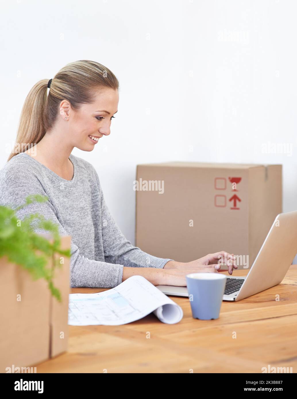 Catching up even on moving day. A young woman sitting in her office ...