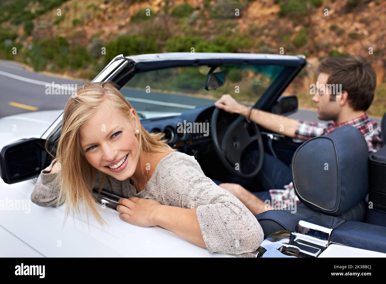 Fancy some adventure. a young couple enjoying a drive in a convertible ...