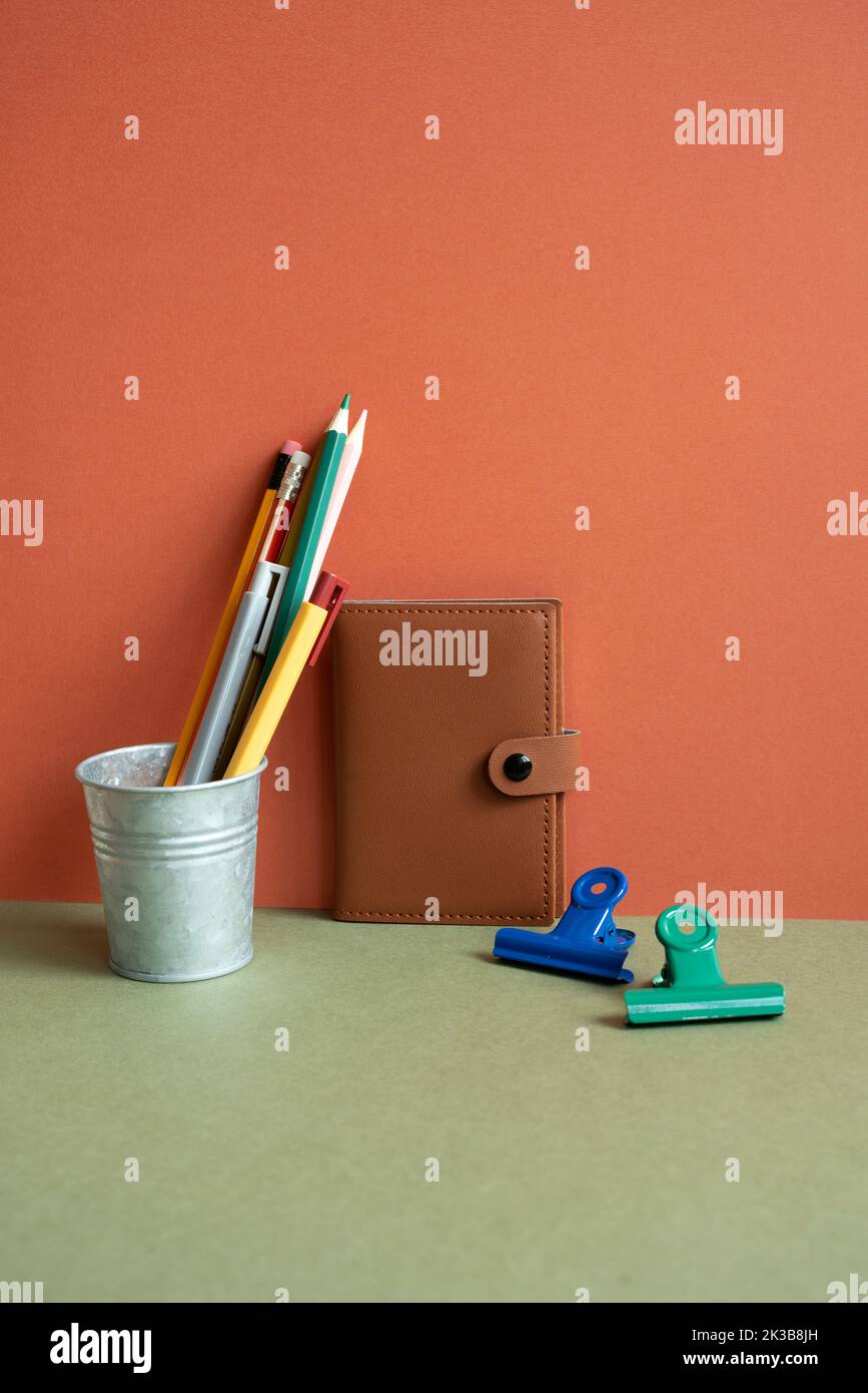 Note, pencil holder, clip on khaki desk. red wall background. workspace ...