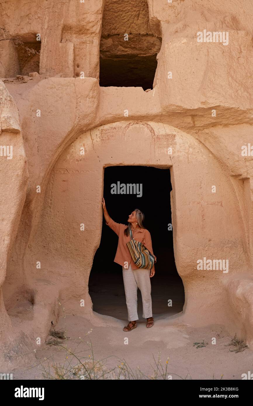 Young woman touring cave in Cappadocia. Open Air Museum, National Park ...