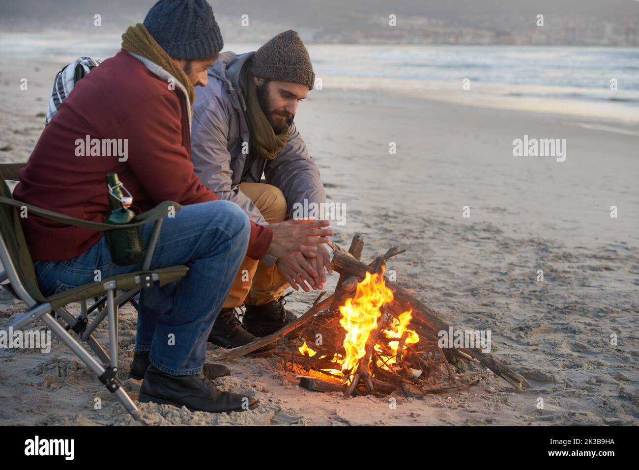 Its a chilly morning by the fire. Two young men sitting around a fire ...