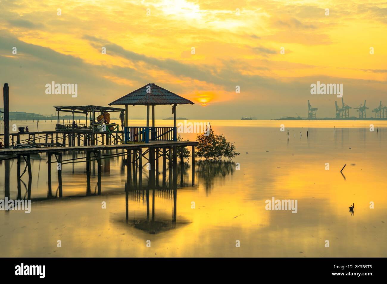 A scenic view of a wooden dock over a calm lake during sunset Stock ...