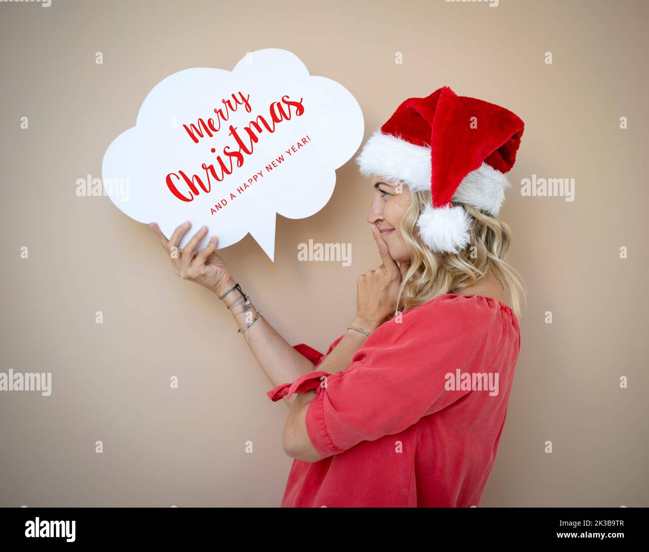 young woman with red christmas hat and red top stands in front of brown ...